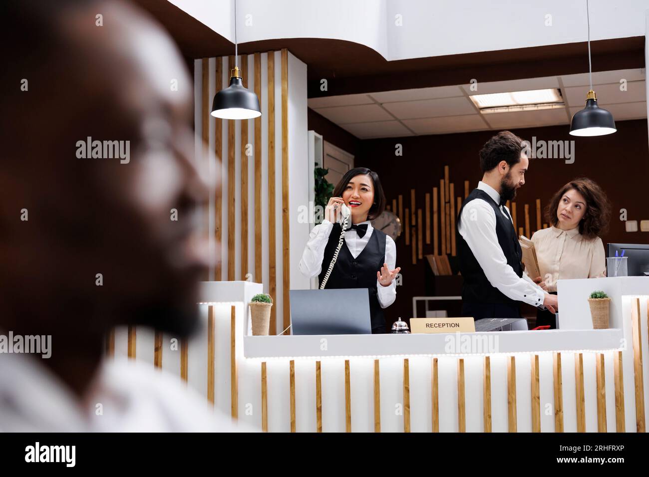 Diverse people standing at front desk working on room reservations ...