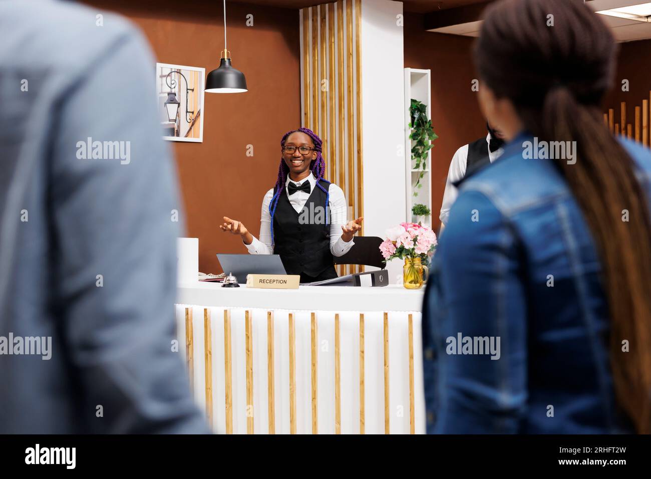 Friendly young African American female receptionist standing at hotel ...