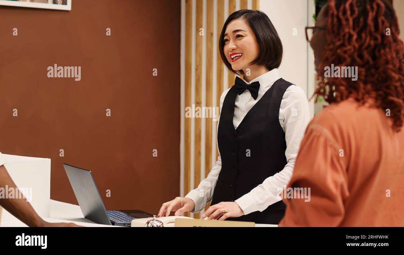 Happy friendly asian receptionist helping guests during check in ...
