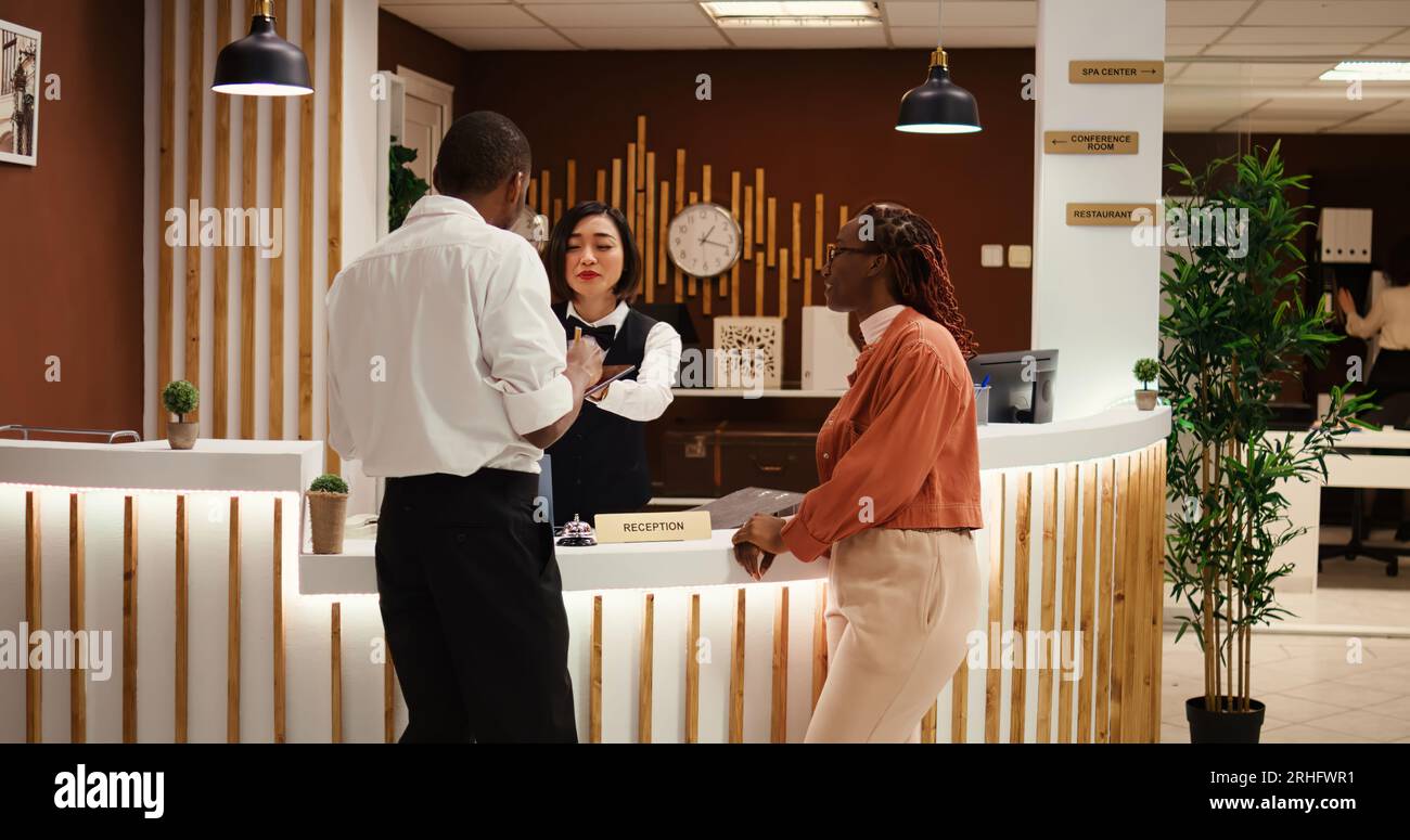 Friendly smiling asian receptionist handing contract on tablet for ...