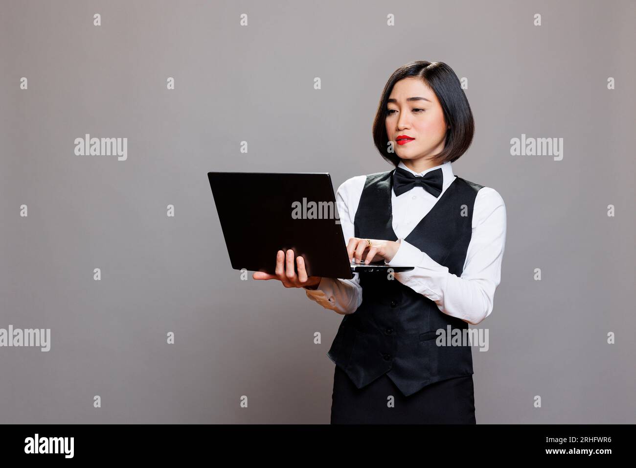Hospitality service receptionist in uniform working on laptop and ...