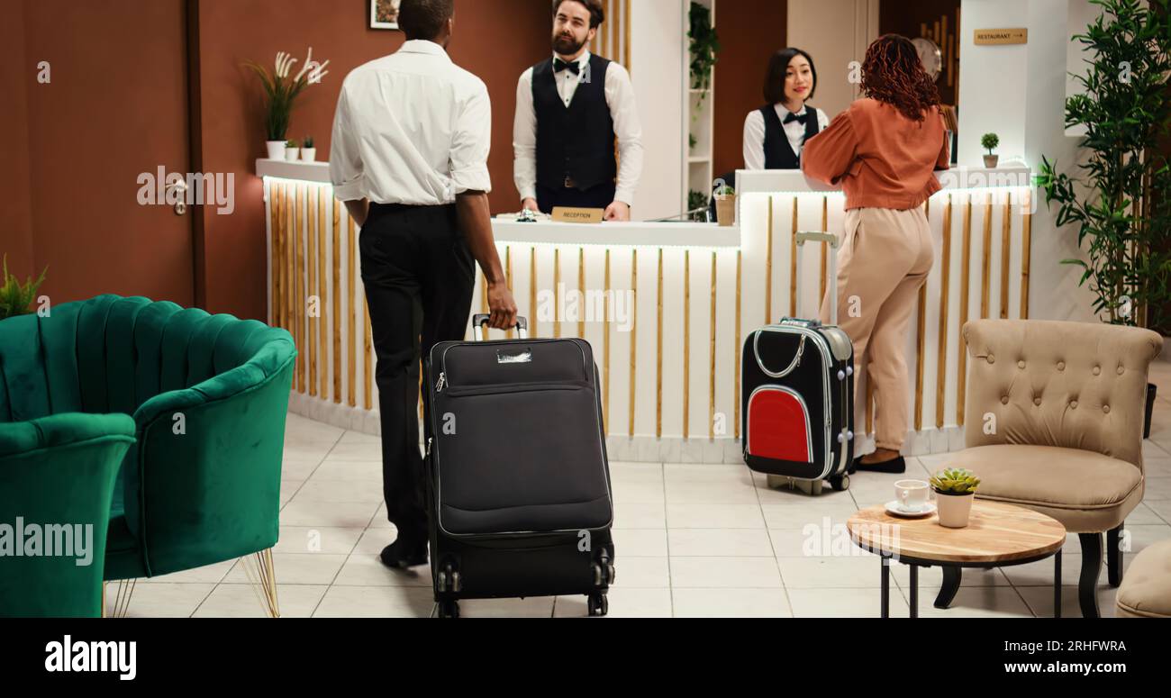 Cheerful smiling concierge personnel helping tourists with ...