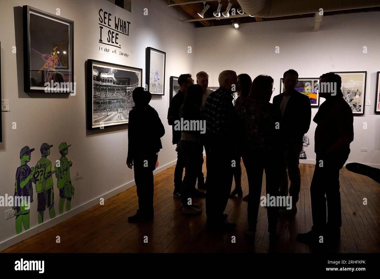 Patrons at the Gallery Victor stand in silhouette as they view the ...