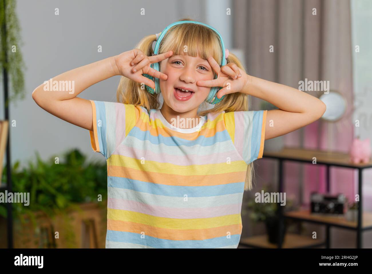 Portrait of happy overjoyed toddler girl kid in wireless headphones ...