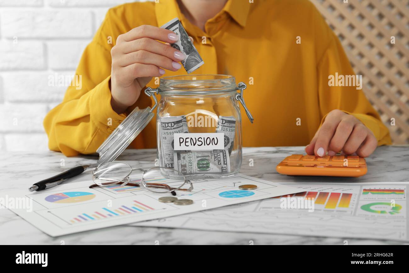 Pension savings. Woman putting dollar banknote into glass jar with ...