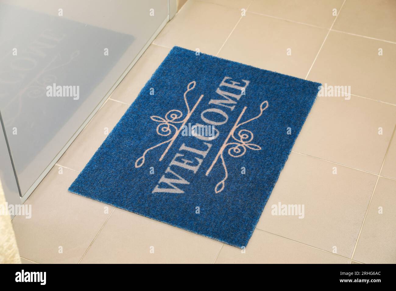 Beautiful blue doormat with word Welcome on floor near entrance Stock ...
