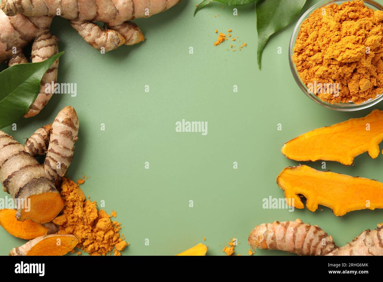 Frame of aromatic turmeric powder, raw roots and leaves on green ...