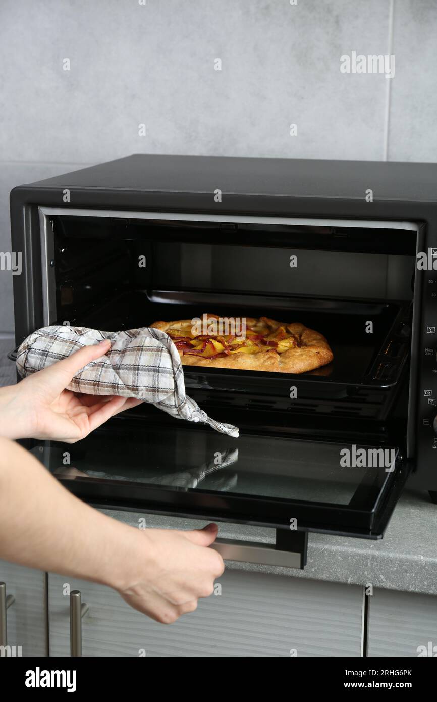 Woman taking baking pan with delicious pie from electric oven in ...