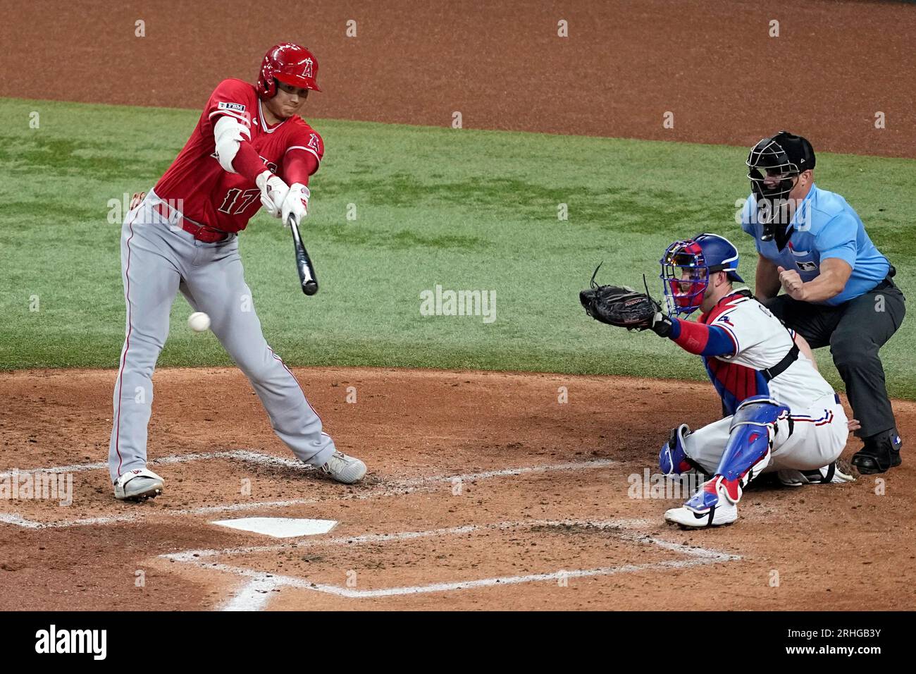 Los Angeles Angels' Shohei Ohtani connects for a single next to Texas Rangers' Mitch Garver and ...