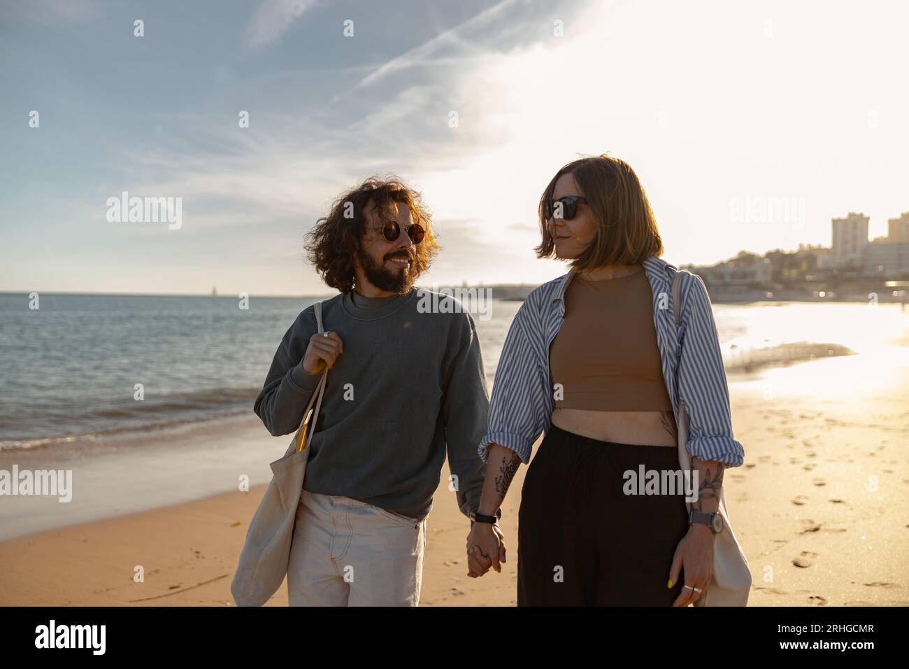 Smiling romantic couple in love is walk holding hands across the beach ...