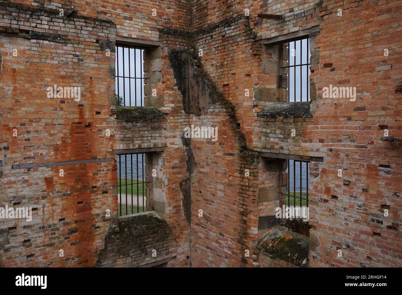 four windows with bars in red brick wall in old jail or penitentiary ...