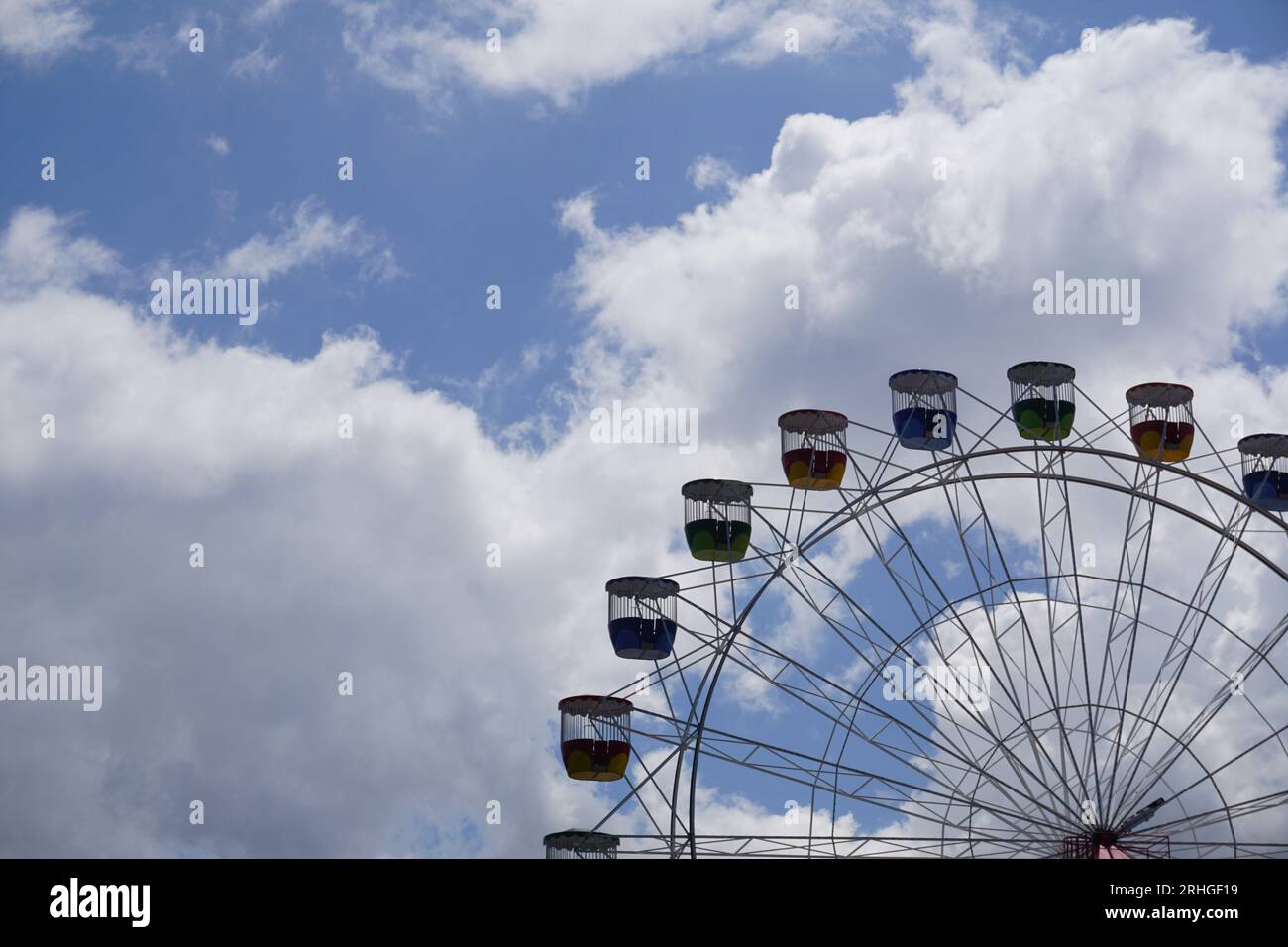 ferris wheel carriages in amusement park seen against partly cloudy sky ...