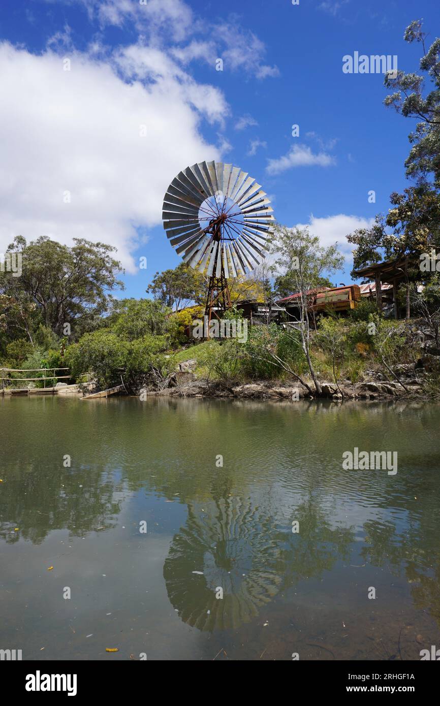 Historical vintage wind mill or water pump next to water with blue sky ...