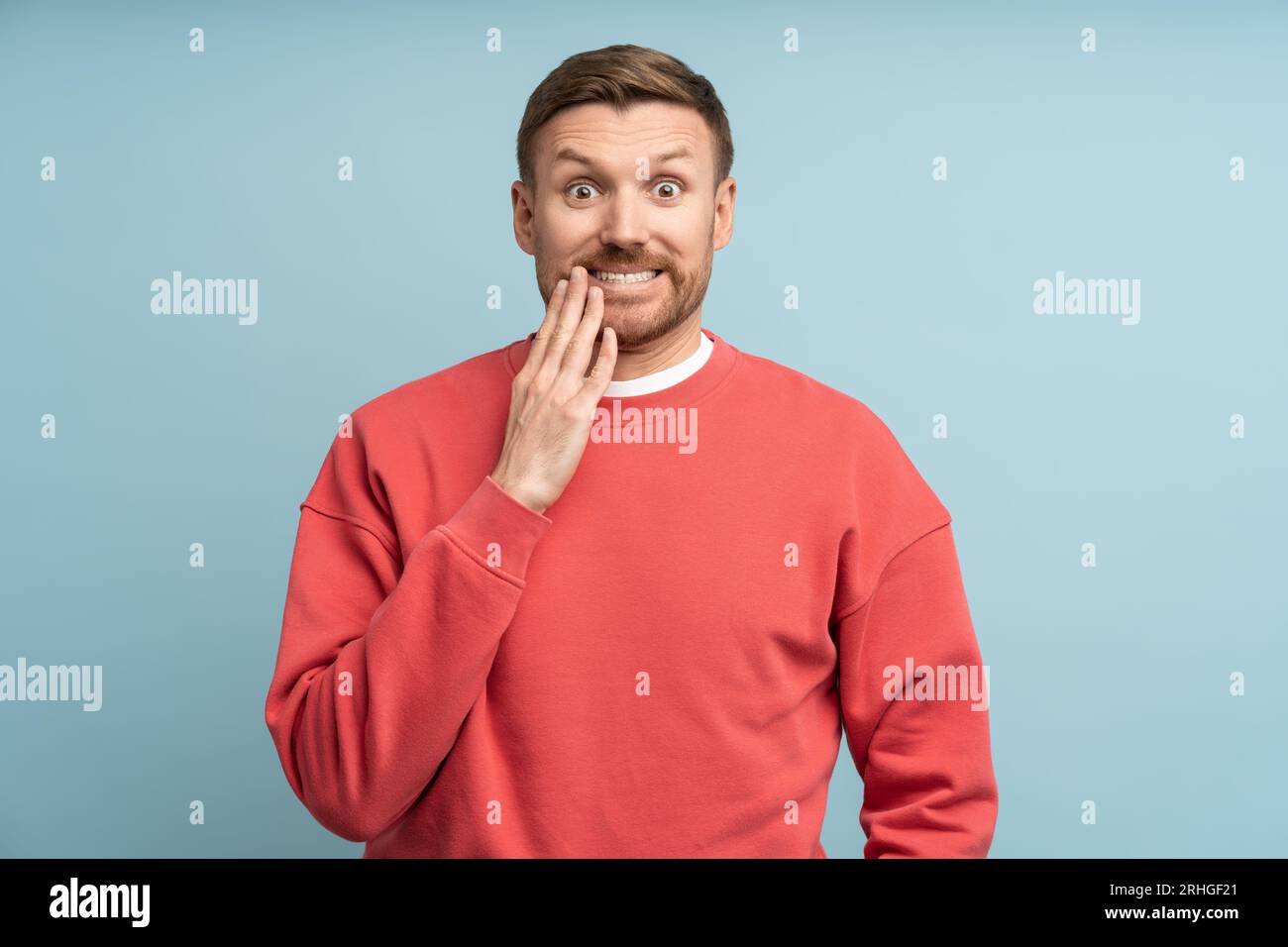 Funny guy covering mouth with hand laughs making big eyes, oops ...