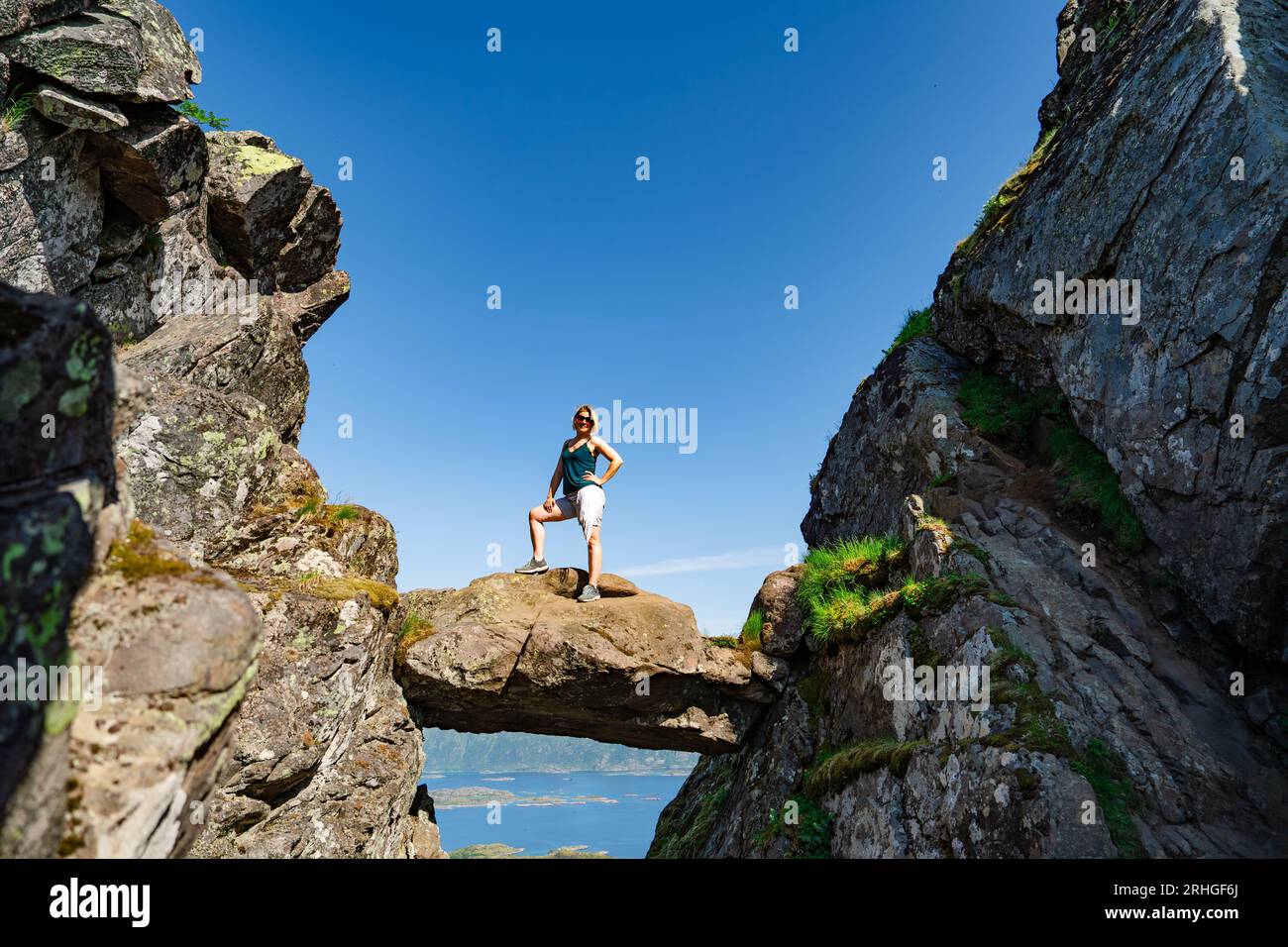 Brave traveler woman standing on hanging stone between rocks ...