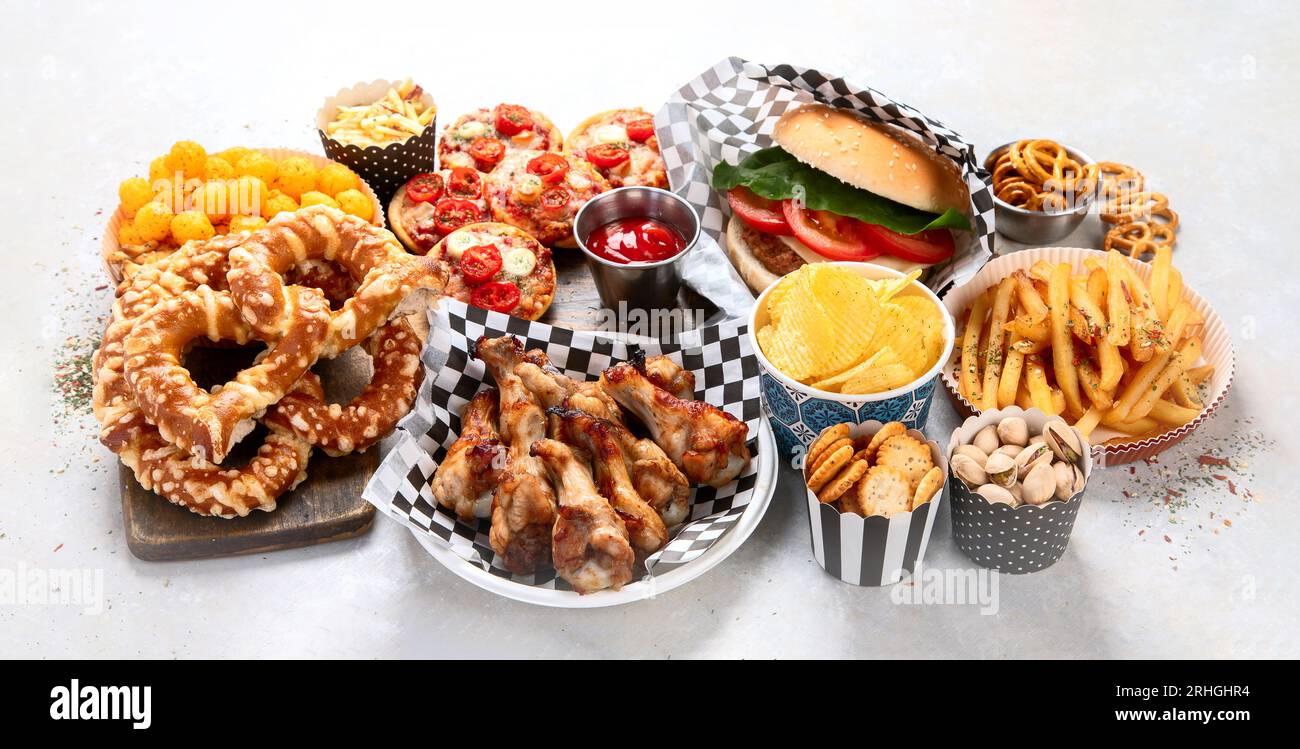 Table scene with large variety of take out and fast foods. Hamburger ...