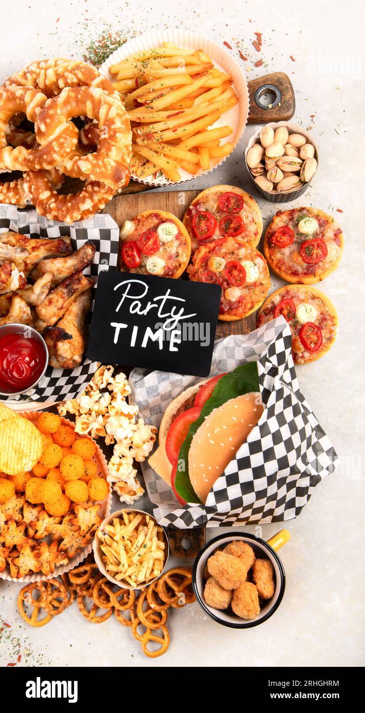 Table scene with large variety of take out and fast foods. Hamburger ...