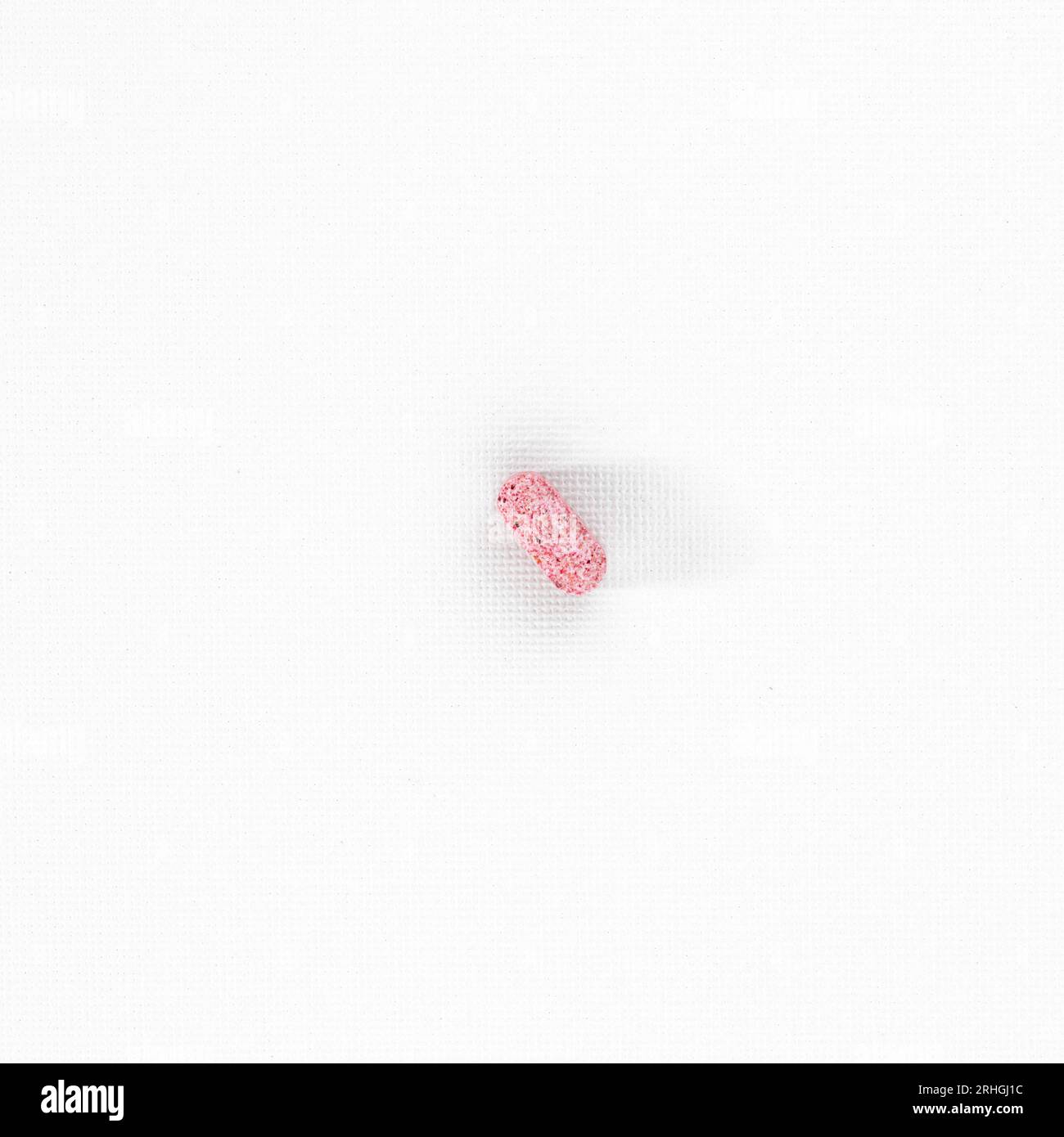 Pink pill on white textured background Stock Photo - Alamy