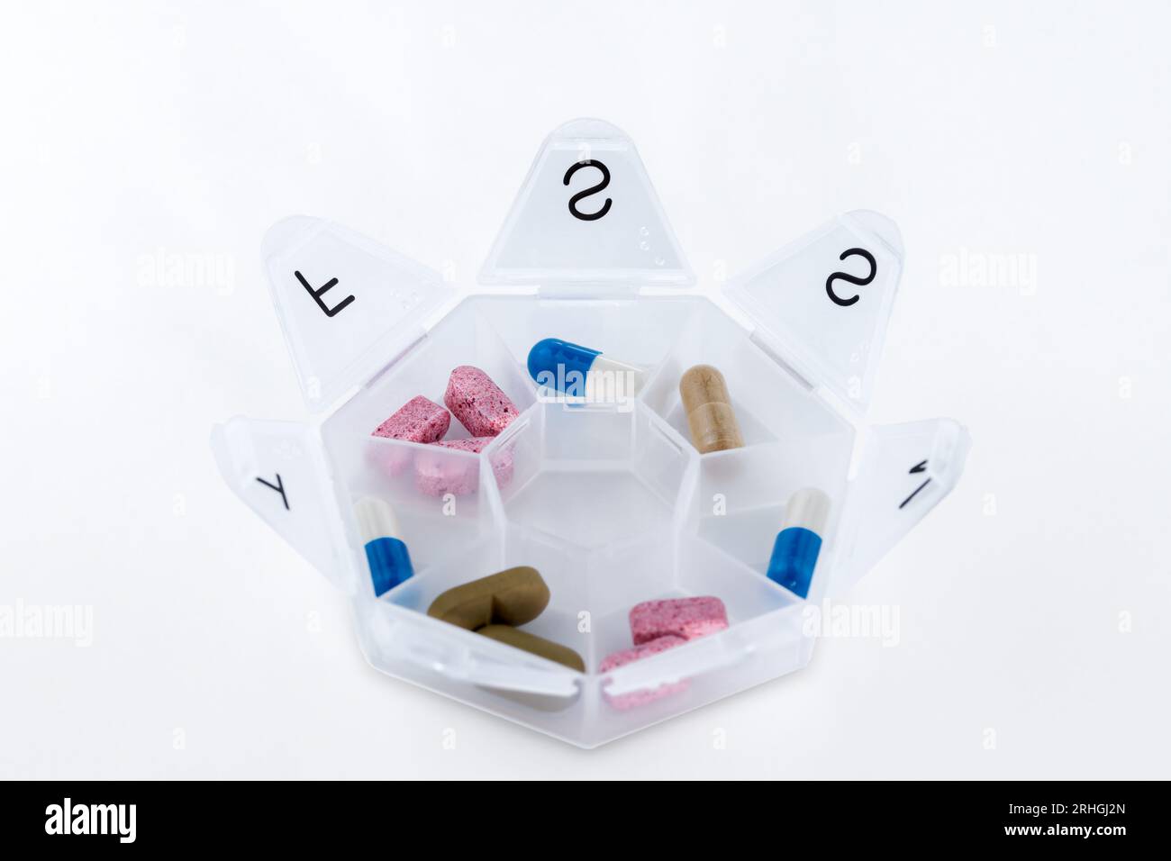 Open pill organizer box storing doses of daily medicine on white table ...