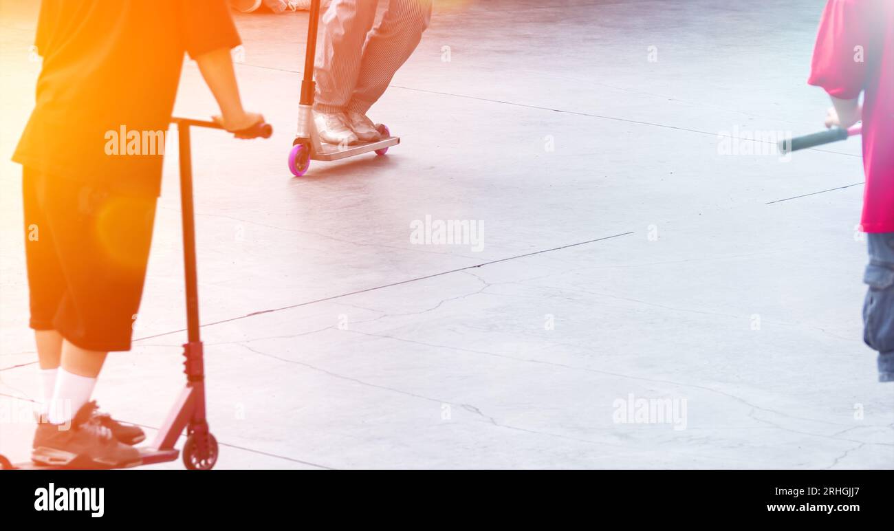Low angle shot of kids riding scooters Stock Photo - Alamy