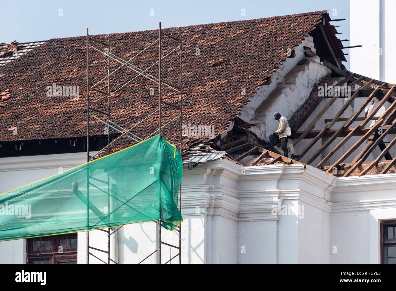Old Goa, India - January 2023: Workers fixing the tiles on the roof ...