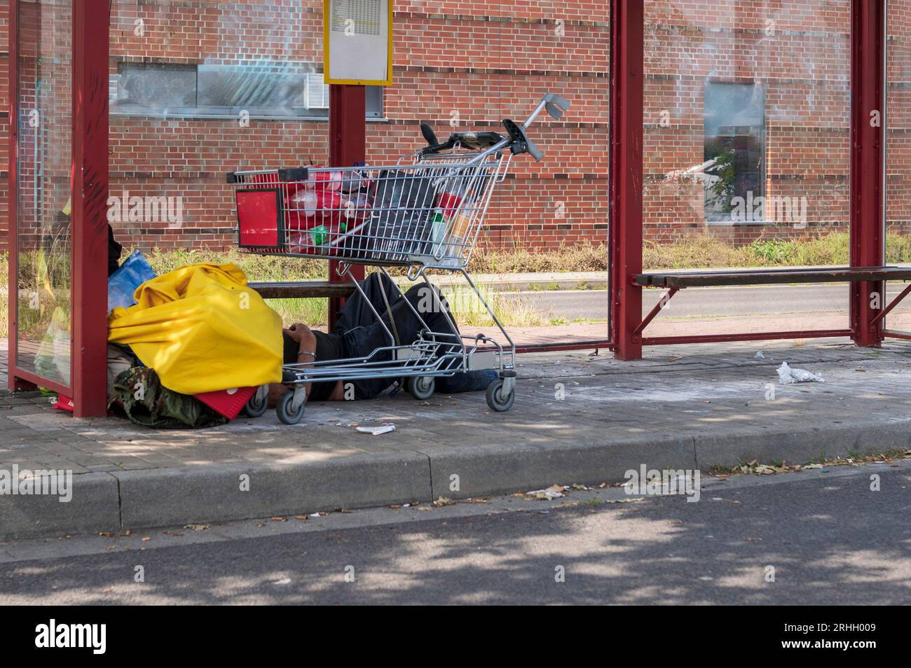 A homeless man with his belongings sleeps in a bus stop Stock Photo - Alamy