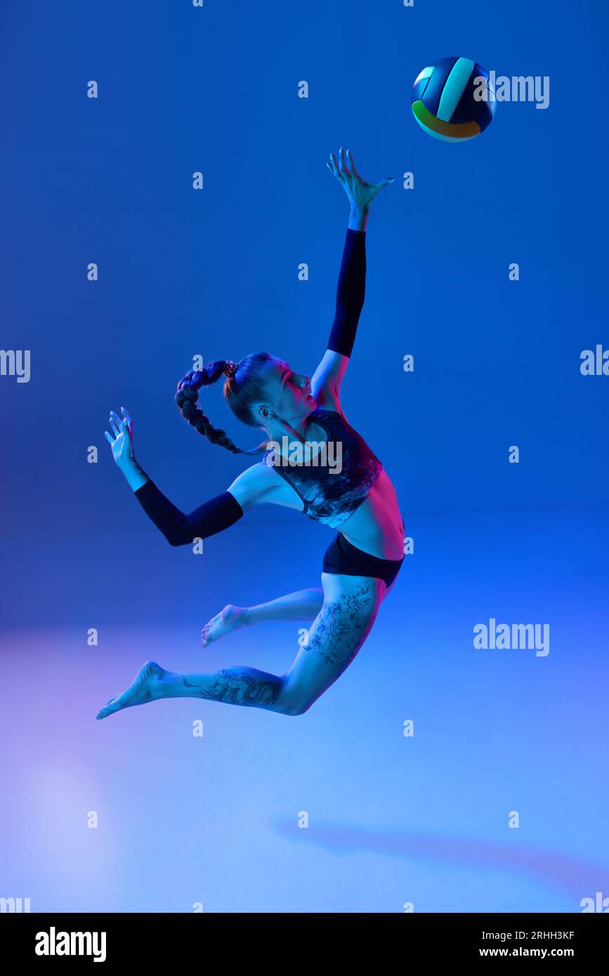 Competitive girl, volleyball player hitting ball with strength against ...