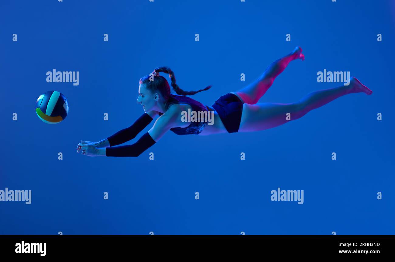 Young woman, volleyball player hitting ball in motion and falling down ...