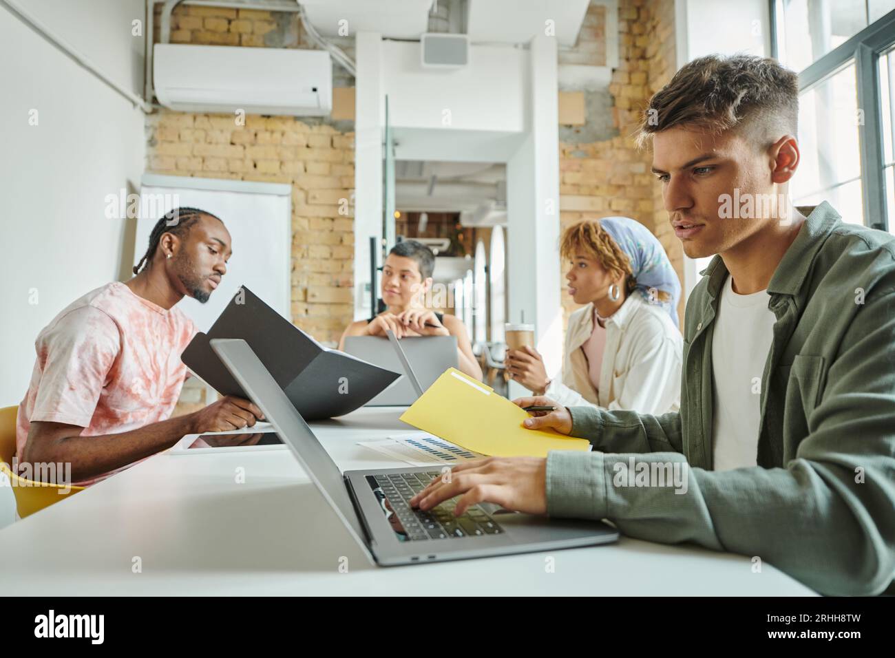 young manager using laptop during meeting with colleagues, diversity ...
