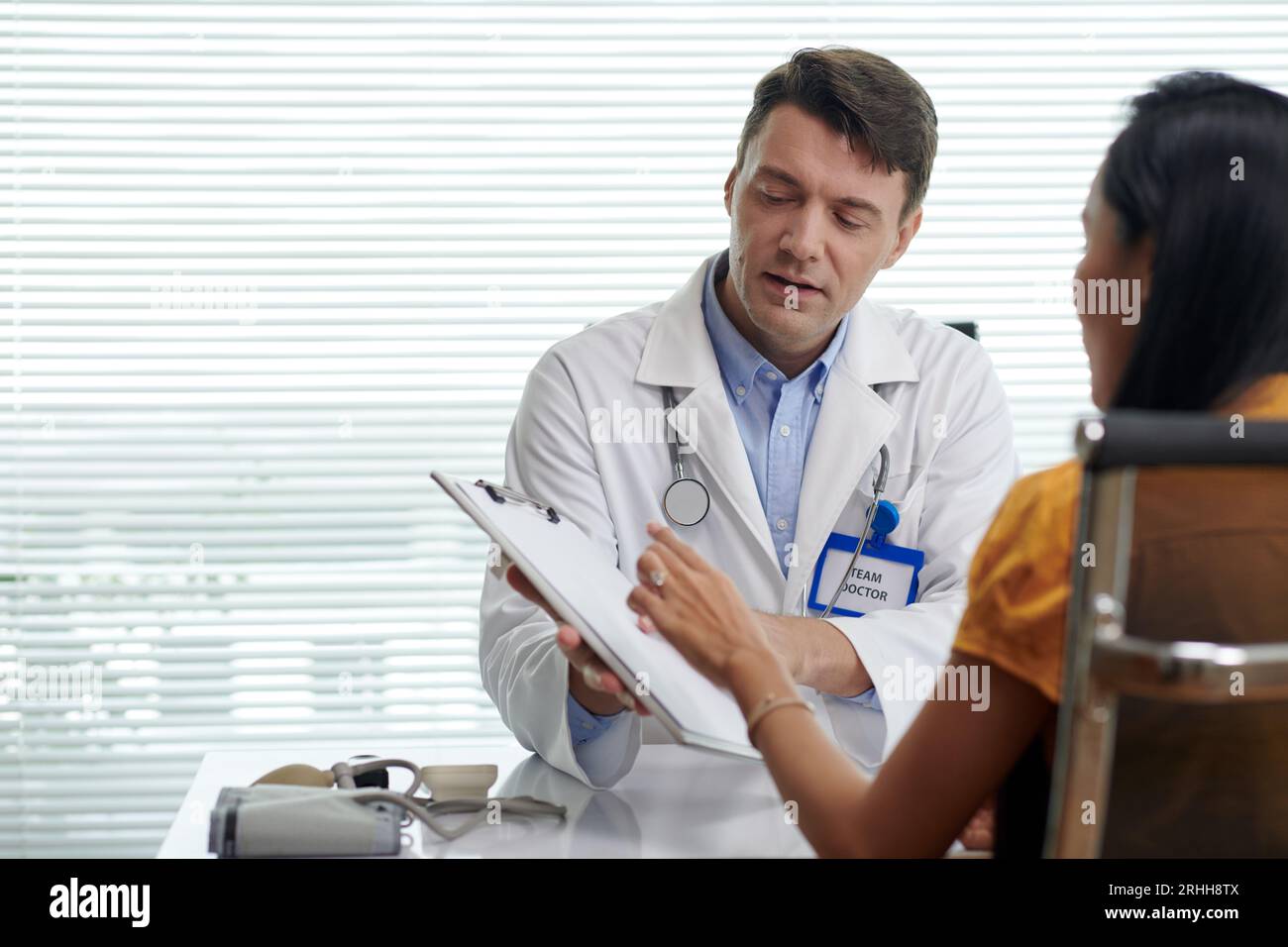 Plastic surgeon talking to client explaining details of medical ...