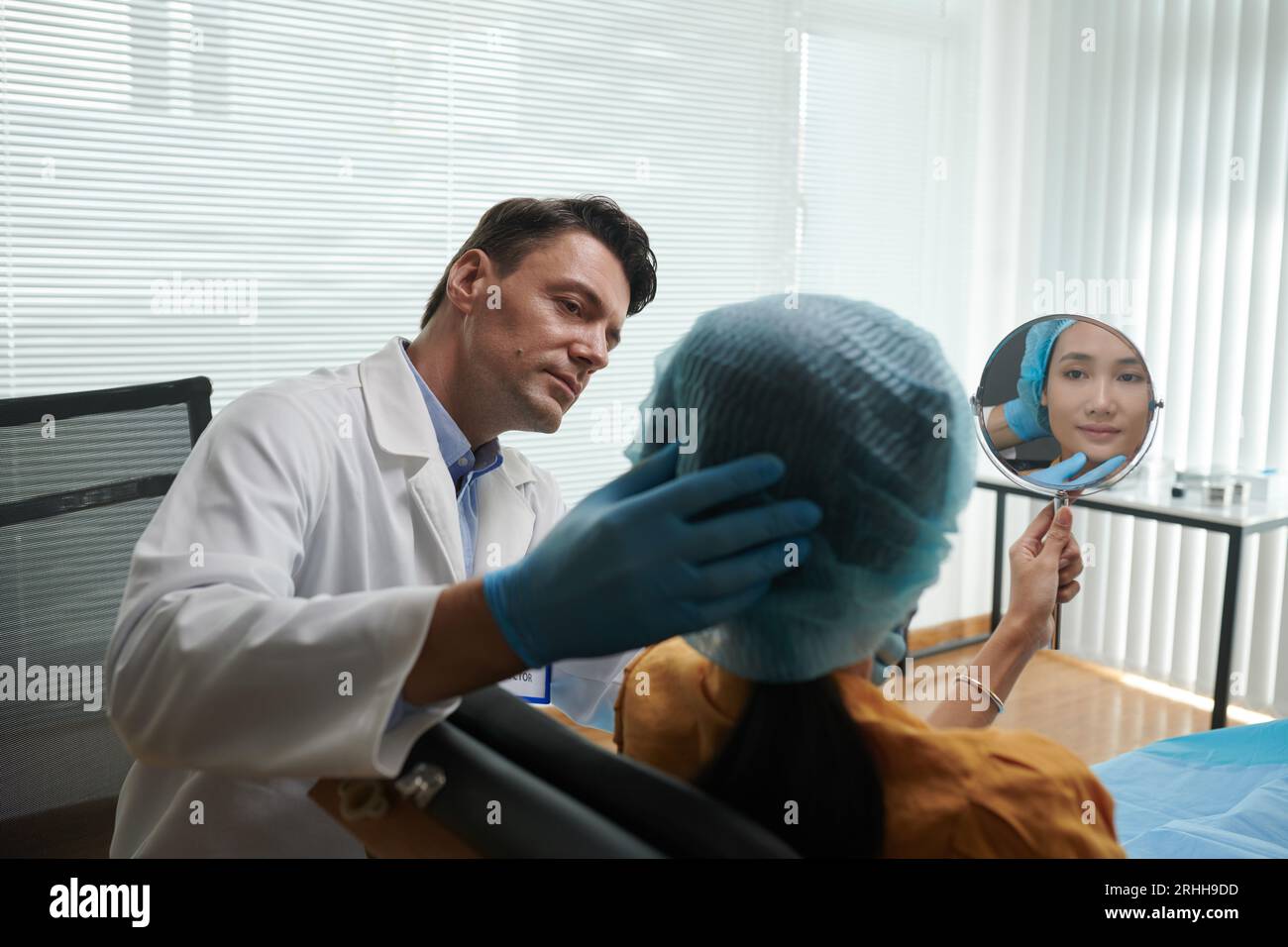 Plastic surgeon letting patient to look in mirror after injections ...