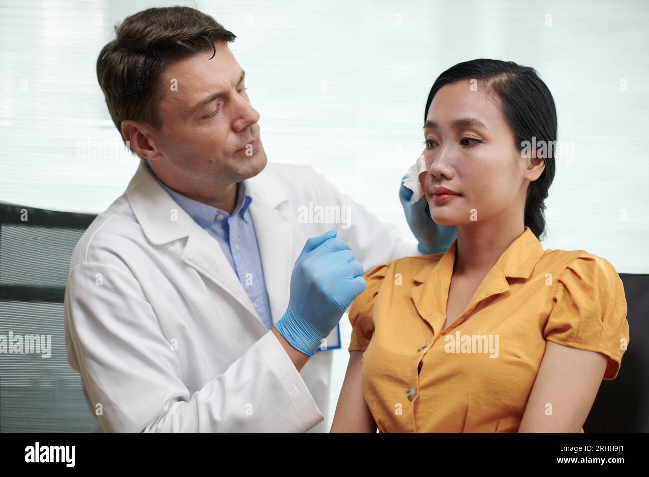 Plastic surgeon removing patch and checking nose of patient after ...
