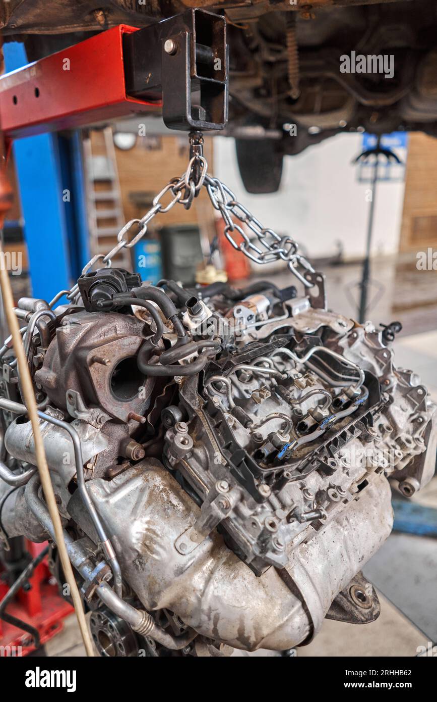 A car mechanic inspects the engine with a flashlight. Engine Block on a ...
