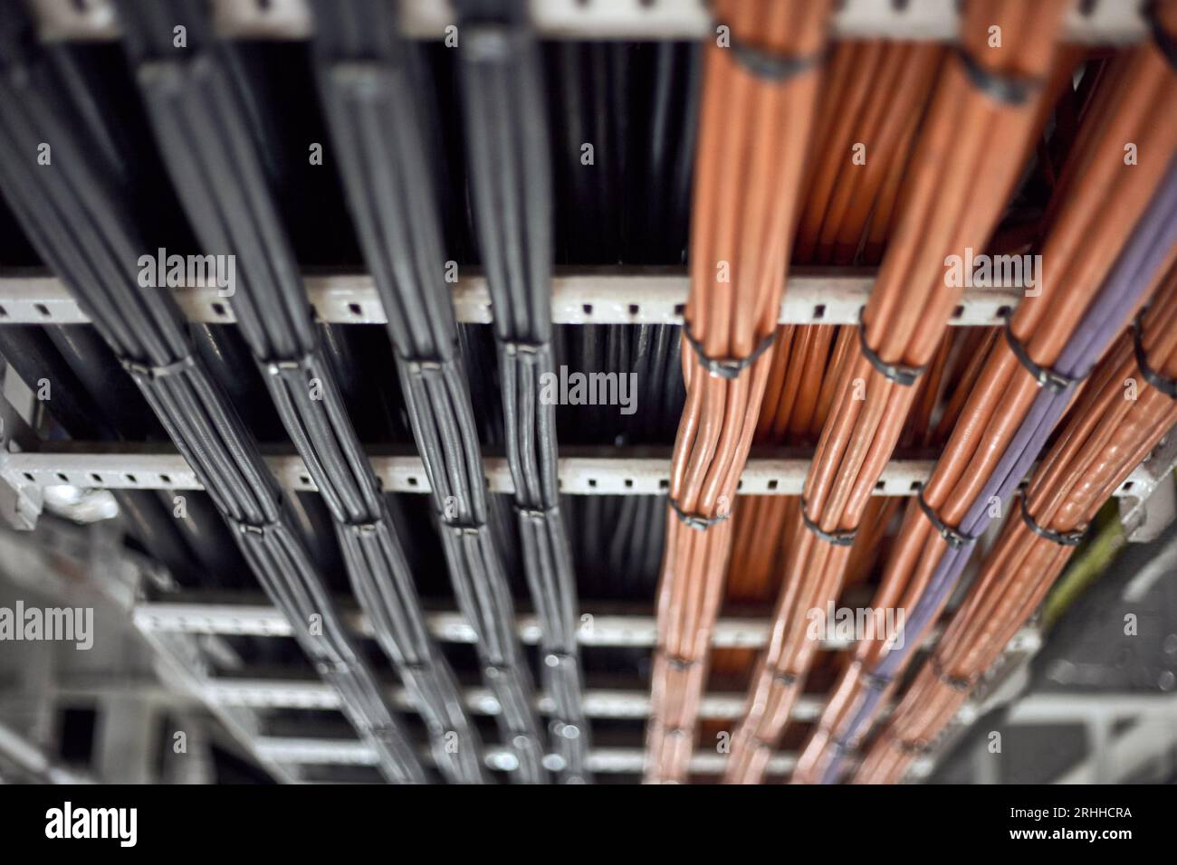 Orange and black power cables vertically secured by metal straps in ...