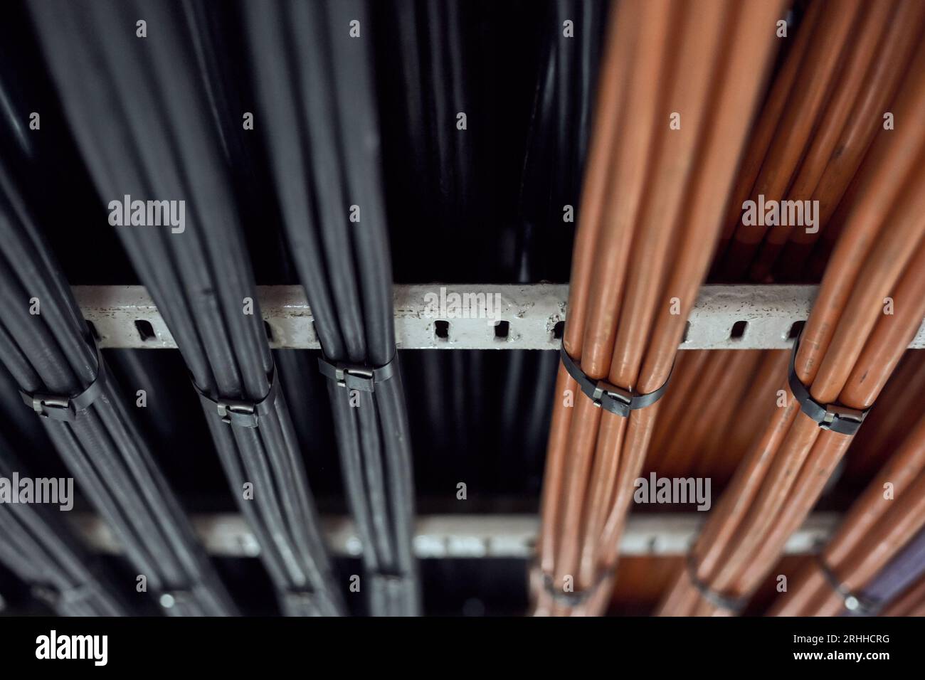 Orange and black power cables vertically secured by metal straps in ...