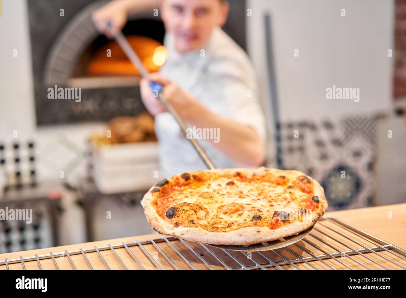 The chef prepares pizza. Raw pizza ready to bake. Cook in a blue apron ...