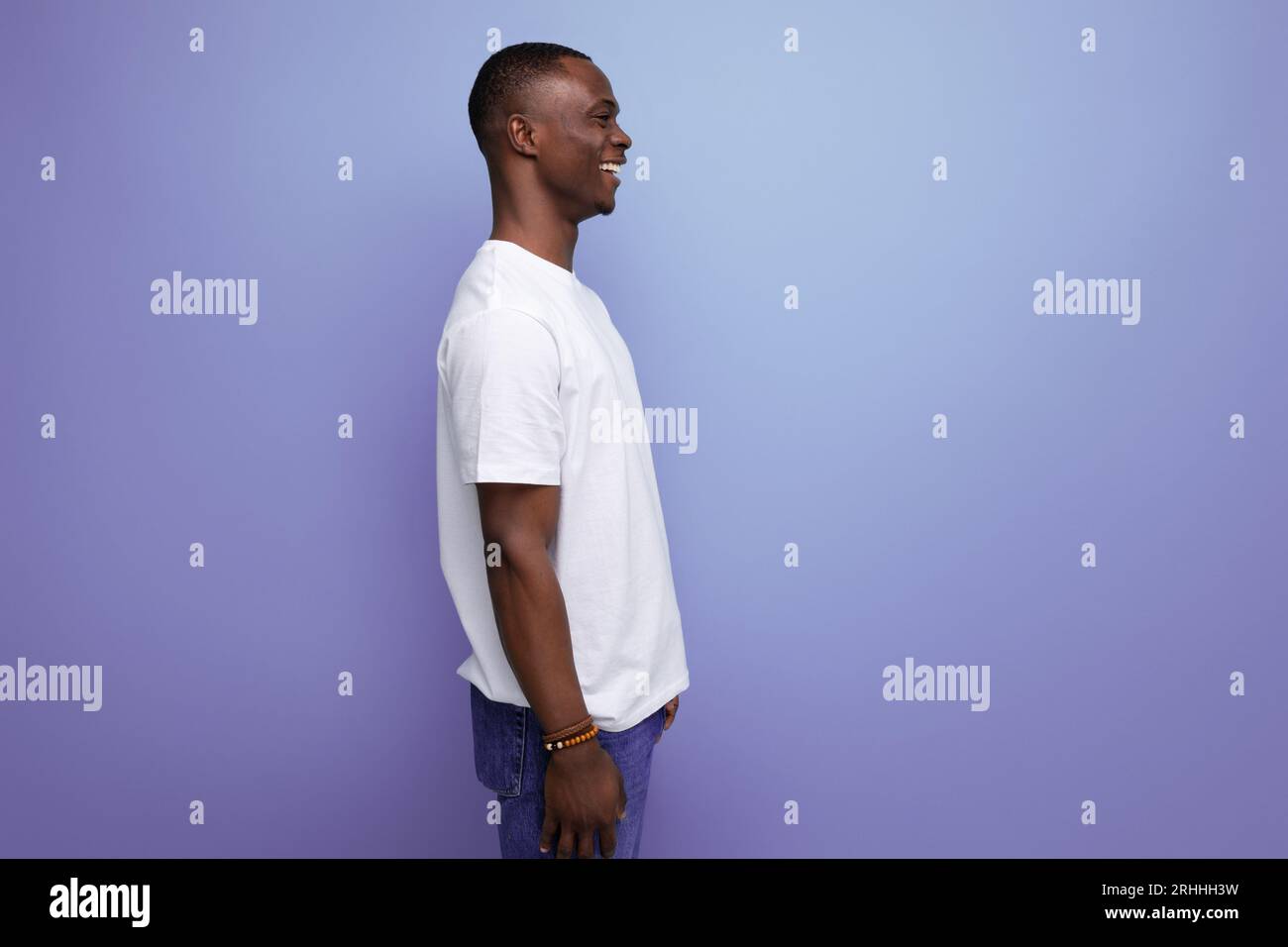 positive young african guy in white t-shirt stands sideways Stock Photo ...