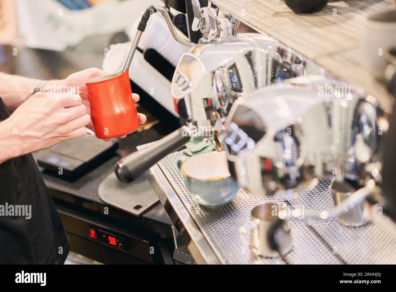 Barista pours cream into the cup of coffee. A small coffee business. A ...