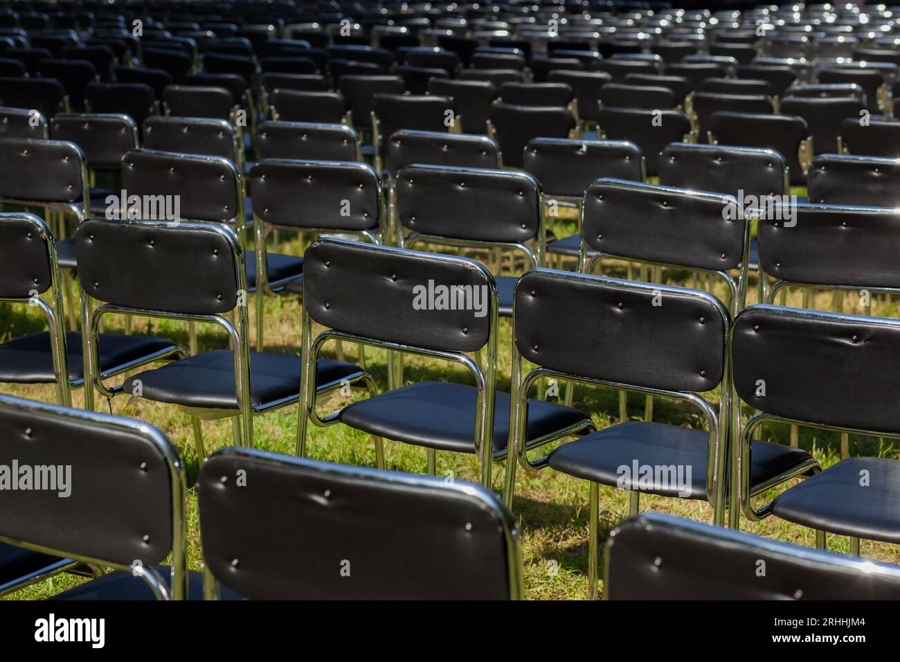 Rows of empty black chairs on grass field Stock Photo - Alamy