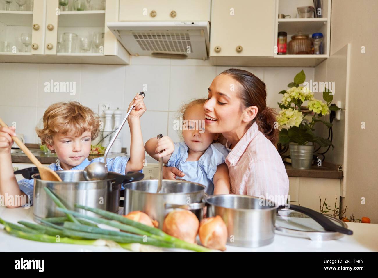 Son and daughter making soup with mother in kitchen at home Stock Photo ...