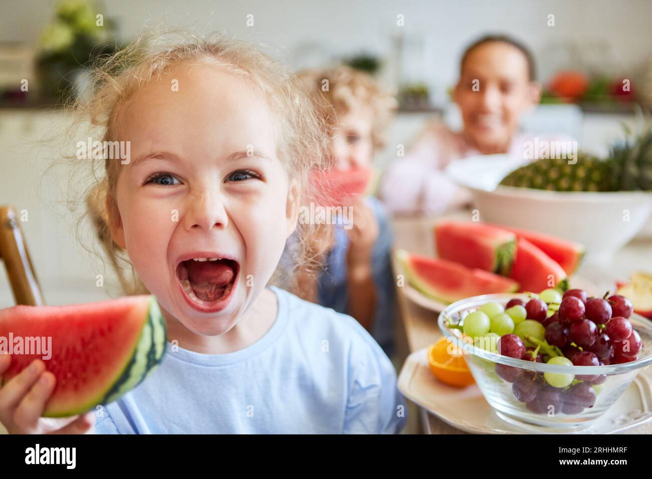 Blond playful girl screaming while holding fresh watermelon slice with ...