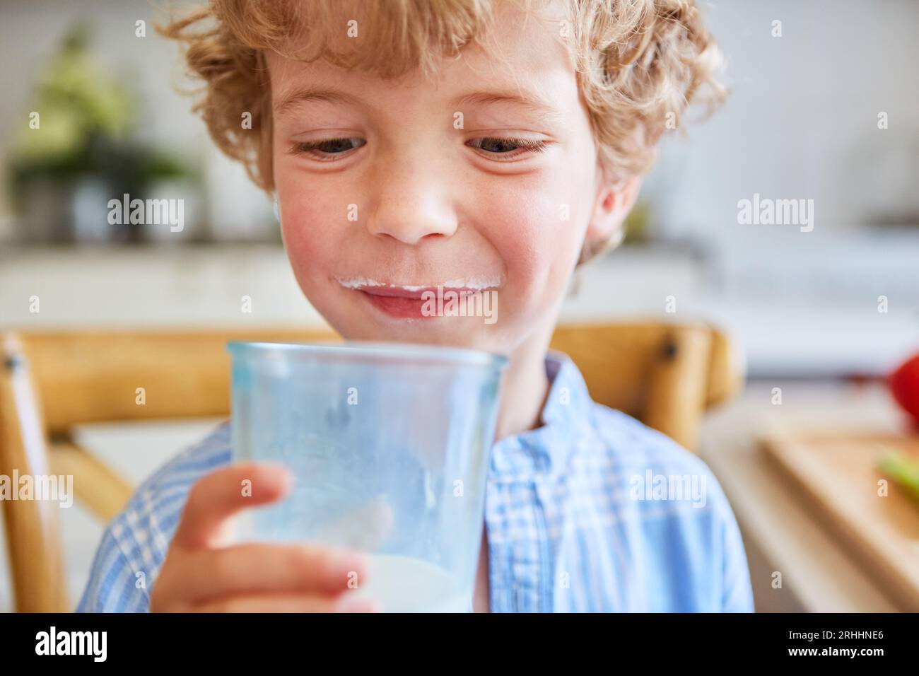 Smiling blond boy holding glass of milk at home Stock Photo - Alamy