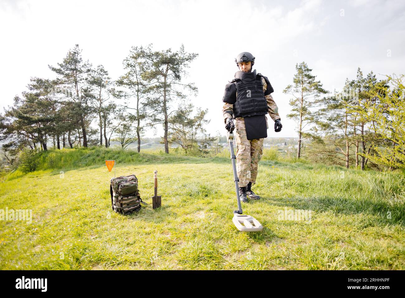 A man in a military uniform and bulletproof vest works in the forest ...