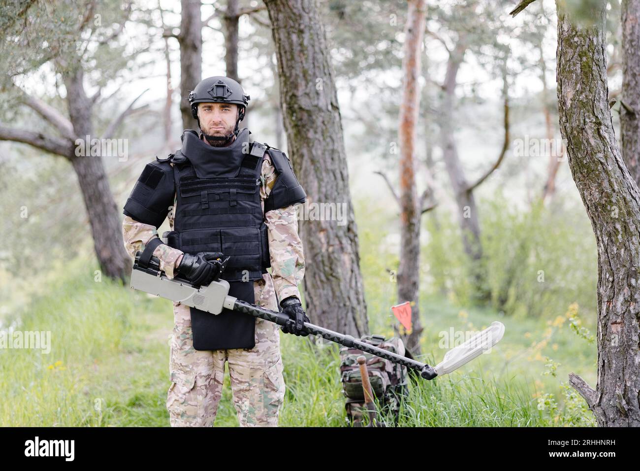 A man in a military uniform and bulletproof vest works in the forest ...