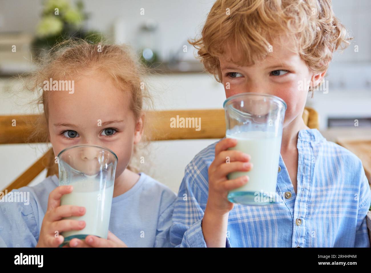 Smiling brother and sister drinking milk from glass at home Stock Photo ...