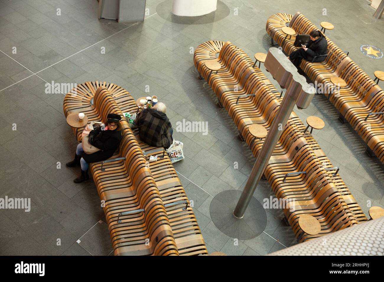 People sit on benches at a quiet King’s Cross Station in London Stock ...