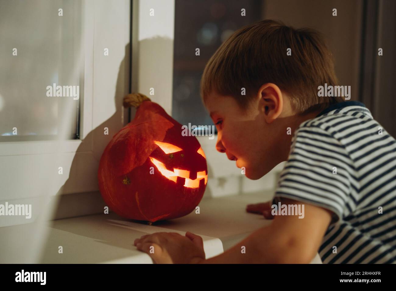 Little boy looking at self made e traditional Jack lantern. Candle lame ...