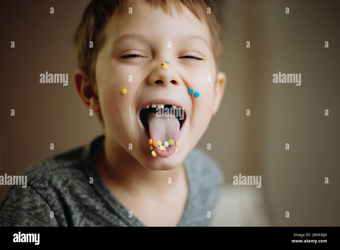 cute little boy putting his tongue out covered with sugar topping ...