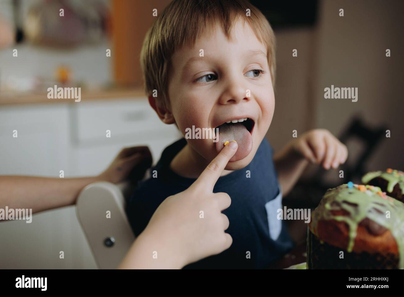 Cute Caucasian baby boy tasting sugar topping with his brother’s hands ...