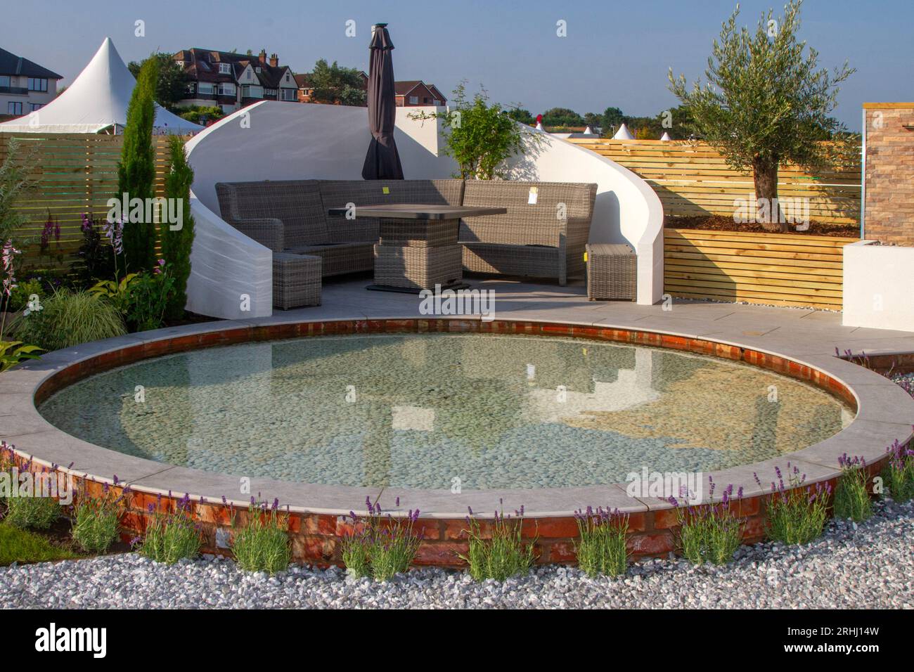 Circular garden pool retreat, Patio with wooden seating & rockery. A ...